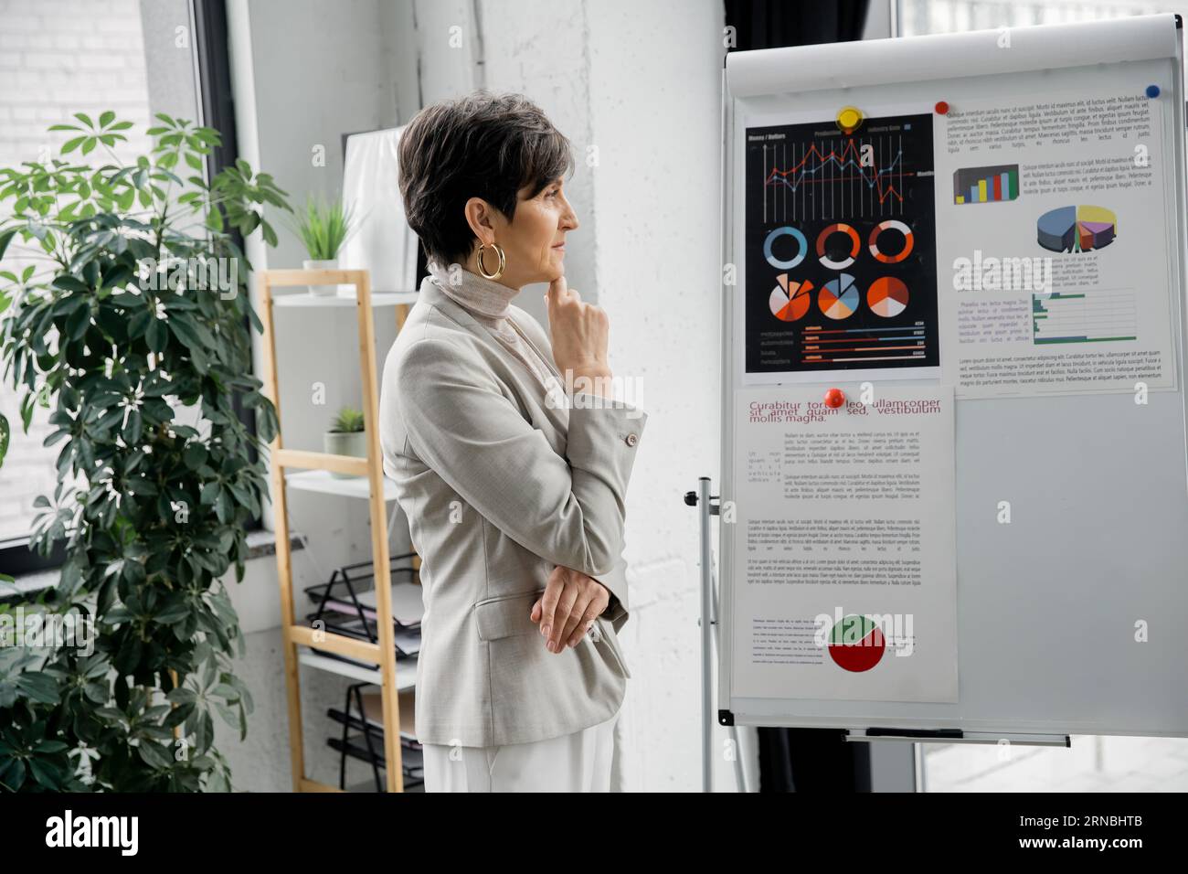 experienced businesswoman thinking near flip chart with infographics in ...