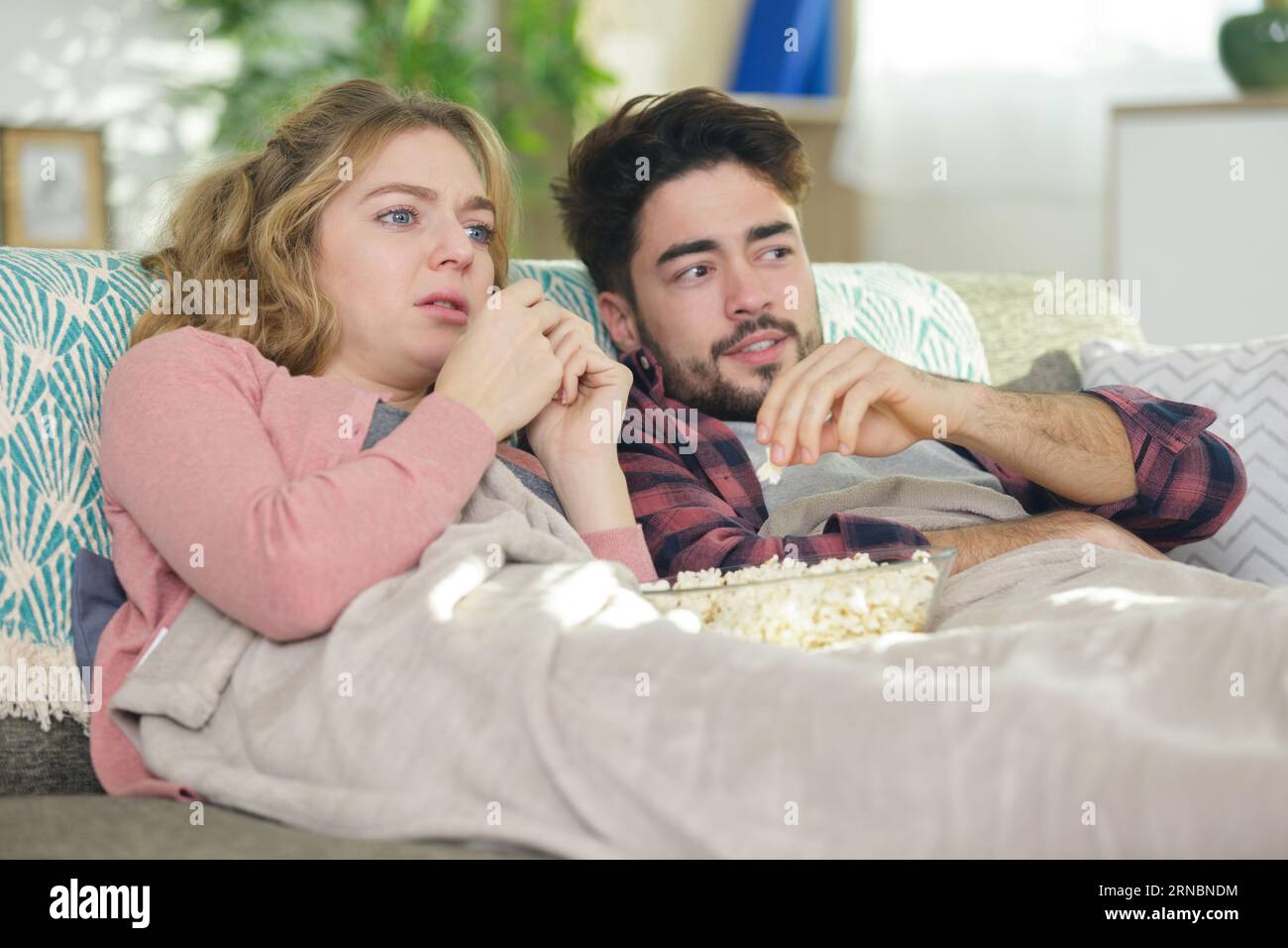 emotional couple snuggled under a blanket watching a movie Stock Photo ...