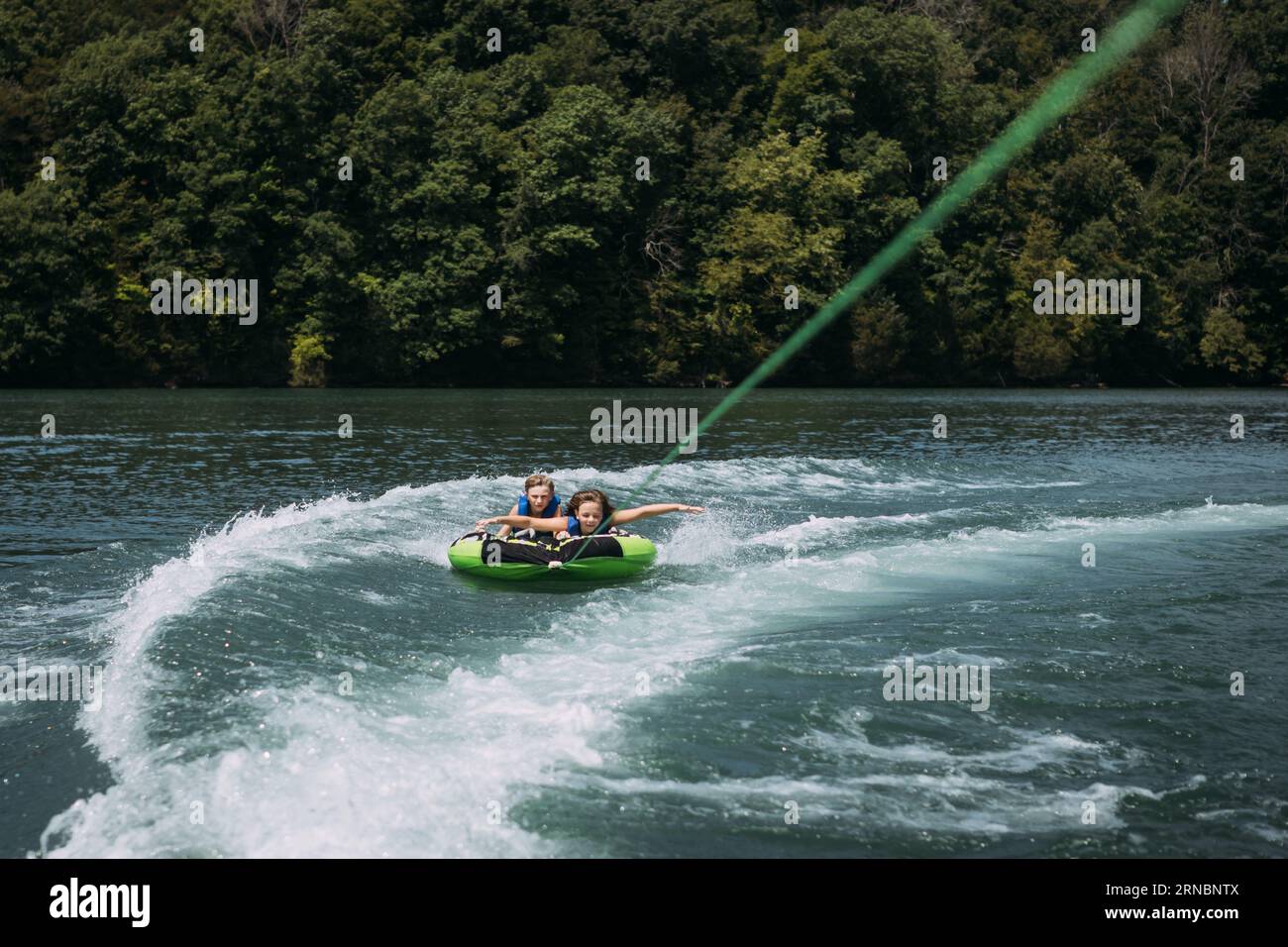 Kids riding on innertube being pulled behind speedboat on summer Stock ...