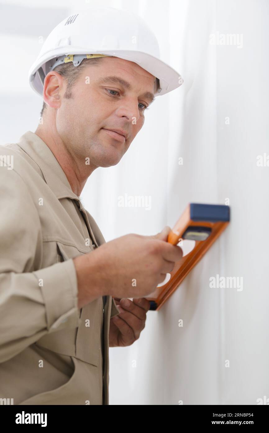 professional worker in helmet is measuring wall with level Stock Photo ...