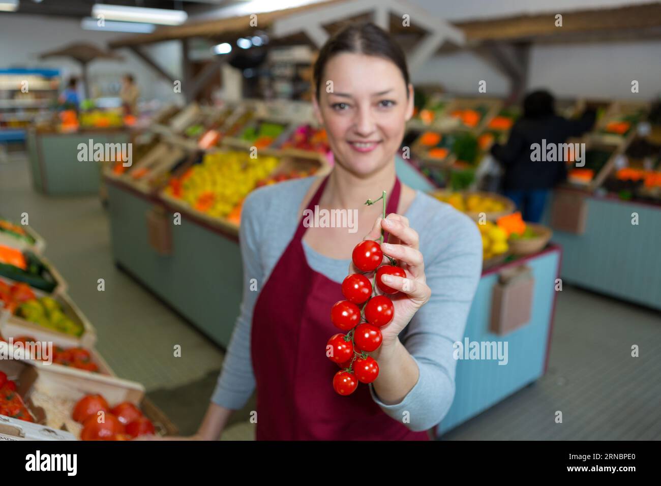 female grocer showing vine cherry tomatoes Stock Photo - Alamy
