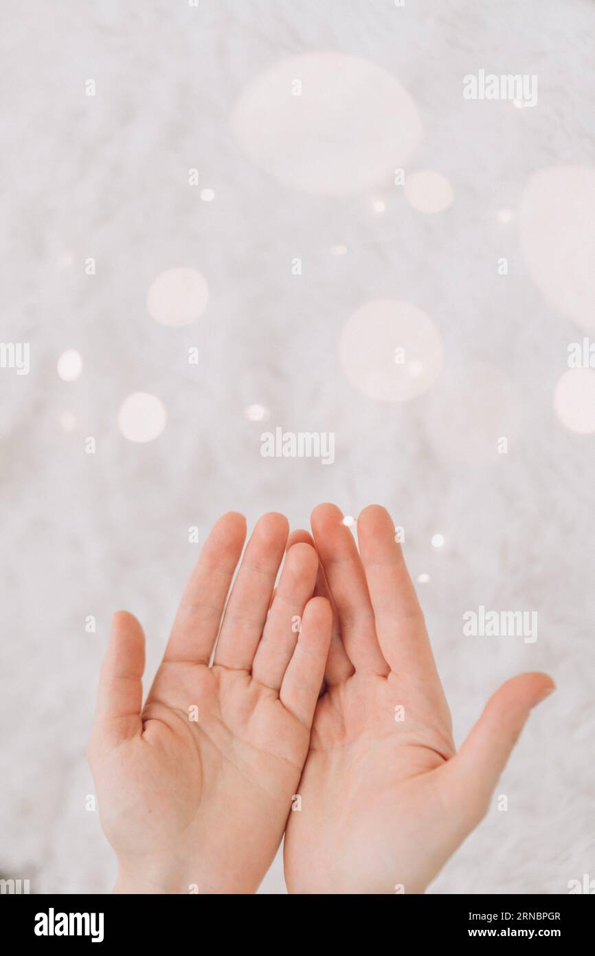 Female hands with palms up with a luminous garland, miracle, goodness ...