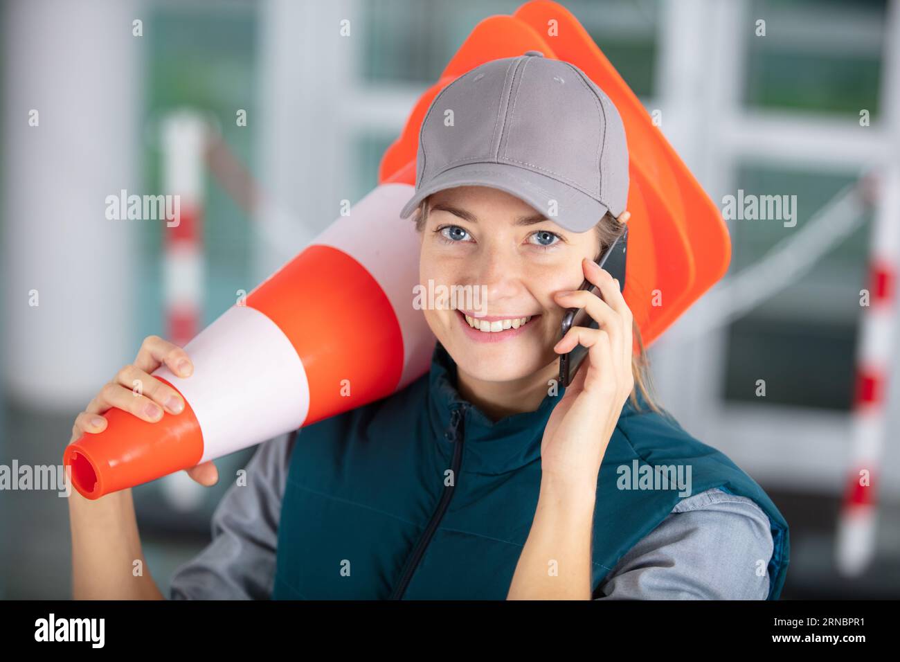 happy female builder holding traffic cone and telephone Stock Photo - Alamy