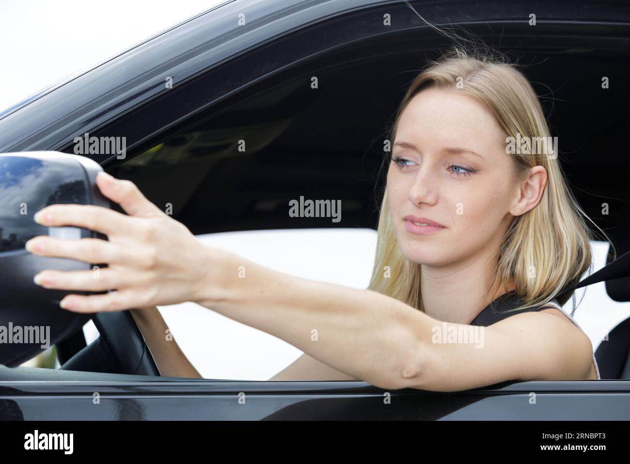 female driver adjusting the side mirror of car Stock Photo - Alamy