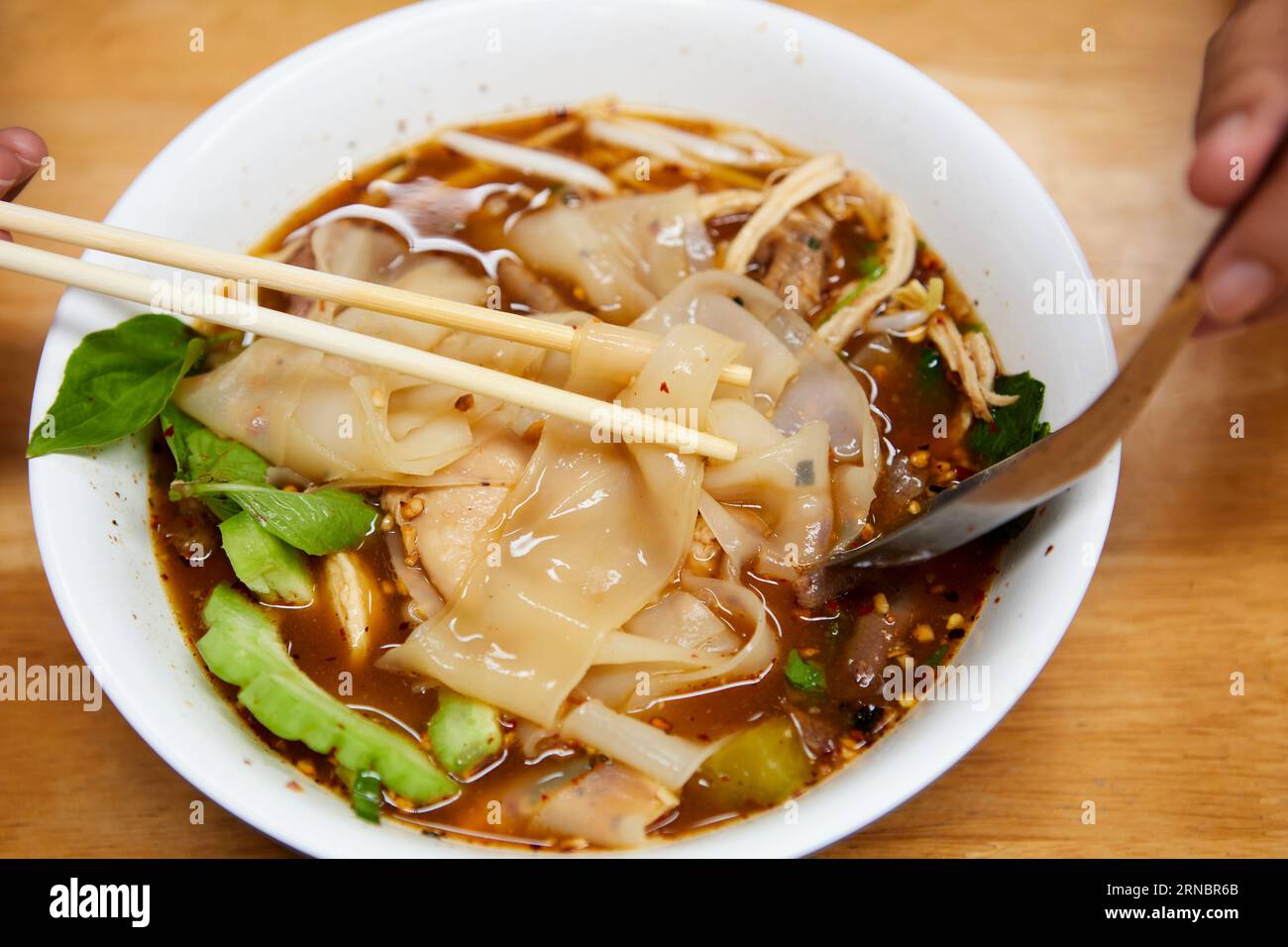 Wide rice noodles with braised chicken meat in a bowl Stock Photo - Alamy