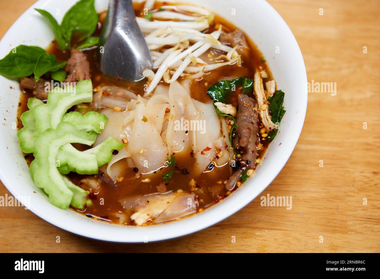 Wide rice noodles with braised chicken meat in a bowl Stock Photo - Alamy