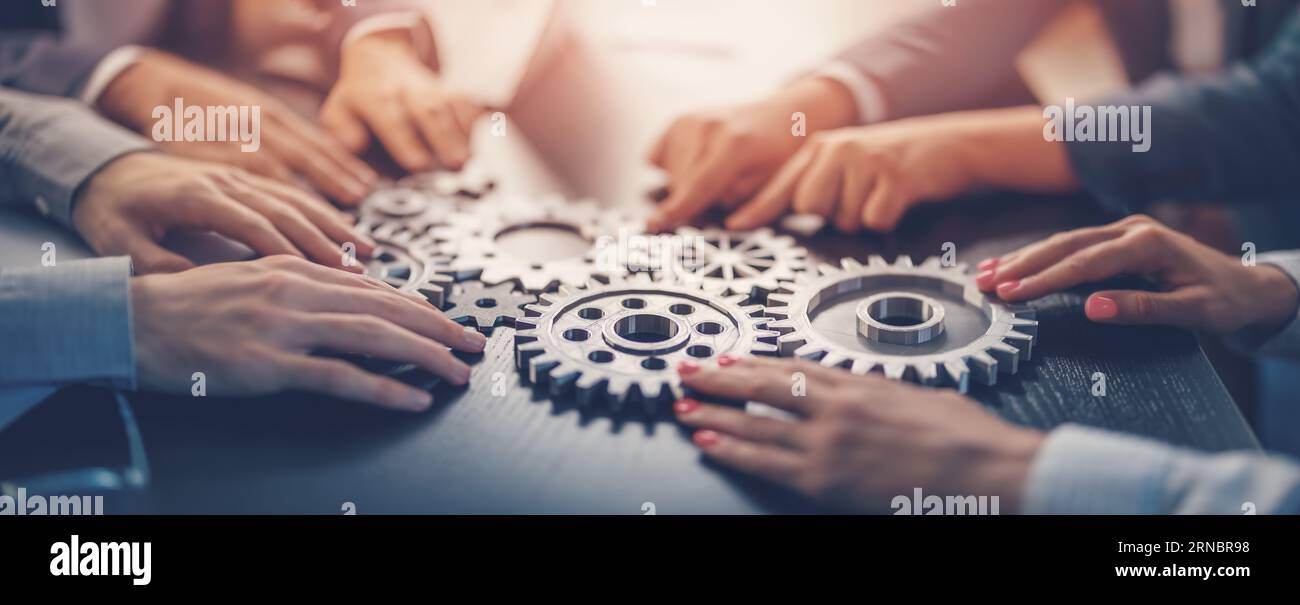 People joining cog wheel on the black desk Stock Photo - Alamy