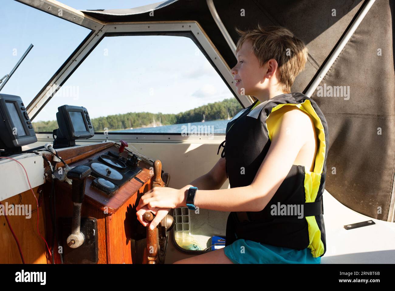 boy happily driving a motorboat out at sea Stock Photo - Alamy