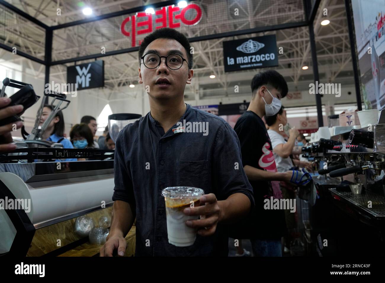 A vendor gives a free coffee to visitors at a booth during the Cafe ...