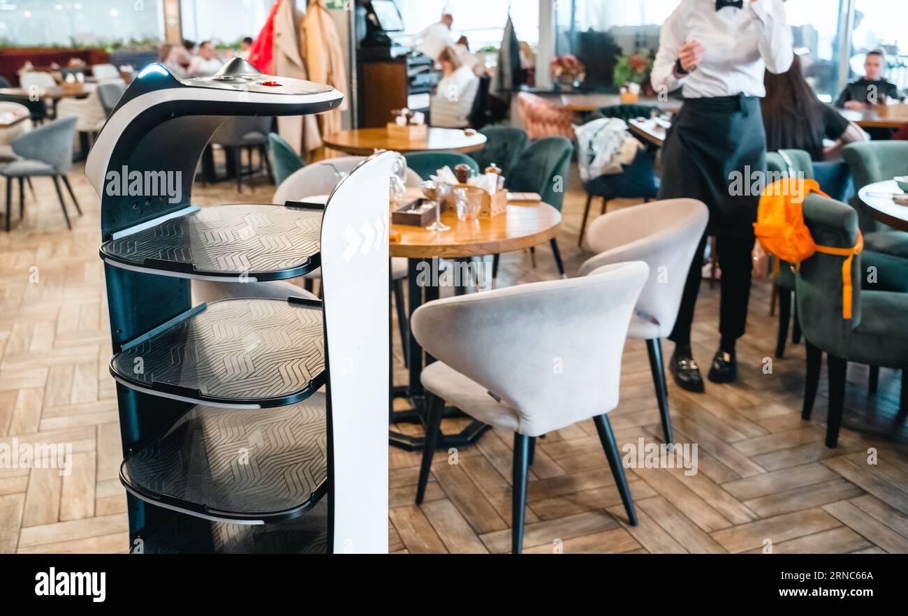 Robot waiter serve food at modern restaurant table.Offering innovation ...