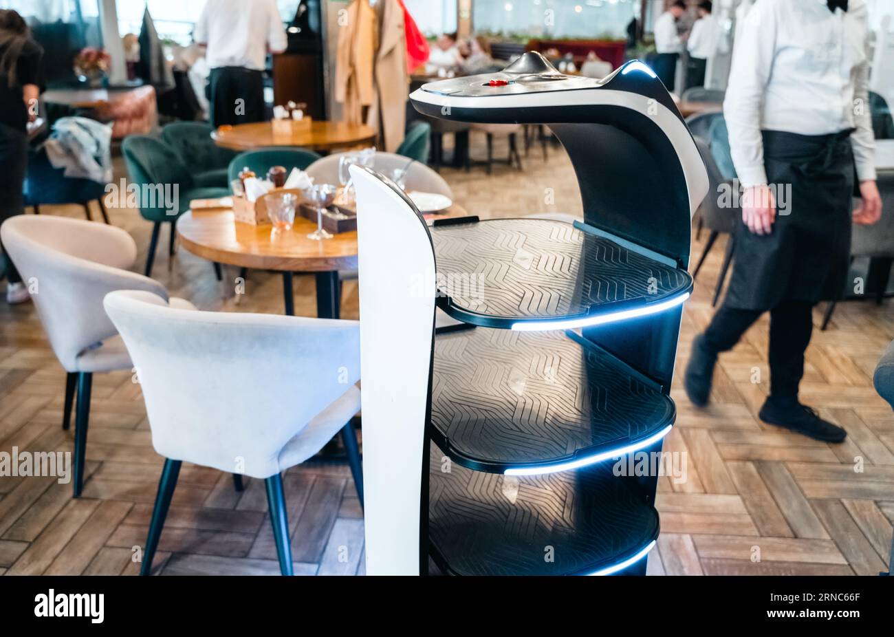 Robot waiter serve food at modern restaurant table.Offering innovation ...
