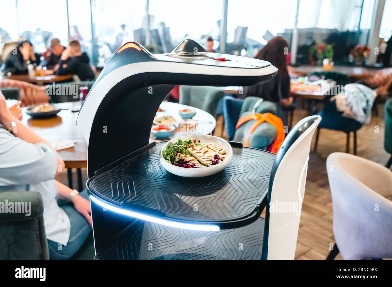 Robot waiter serve food at modern restaurant table.Offering innovation ...