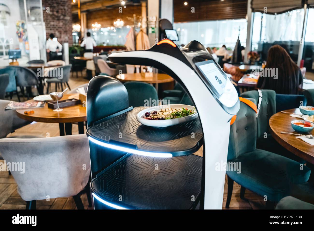 Robot waiter serve food at modern restaurant table.Offering innovation ...