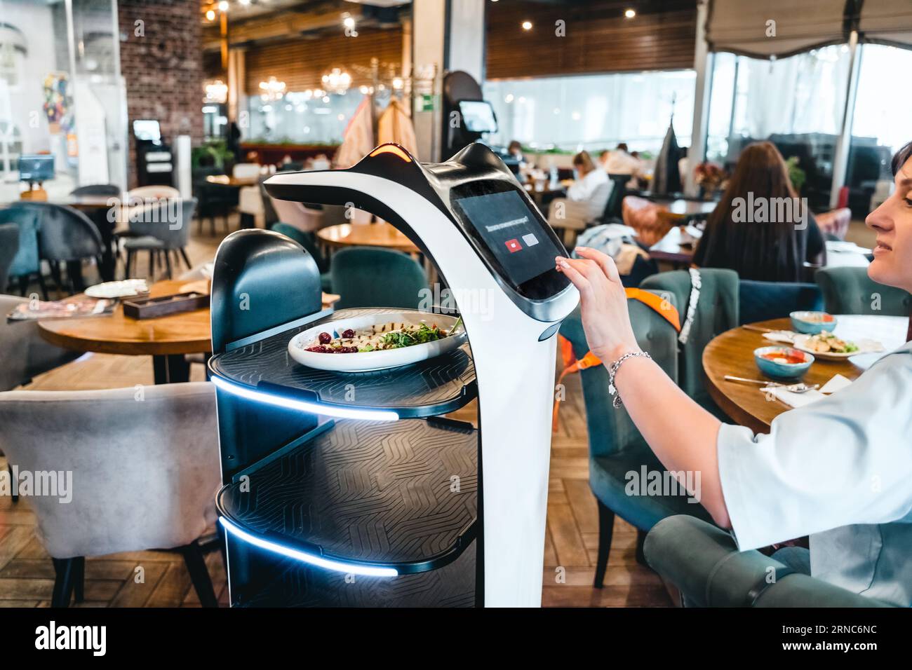 Robot waiter serve food at modern restaurant table.Offering innovation ...