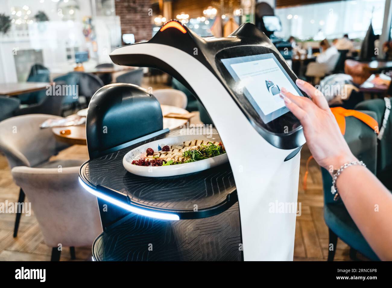 Robot waiter serve food at modern restaurant table.Offering innovation ...