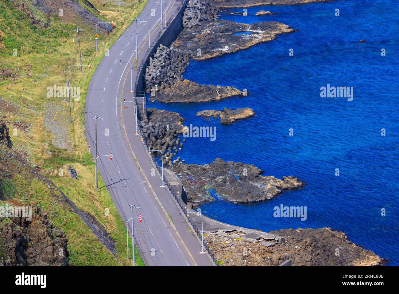 Aerial view of empty curved road on rugged Sea of Japan coast and blue ...