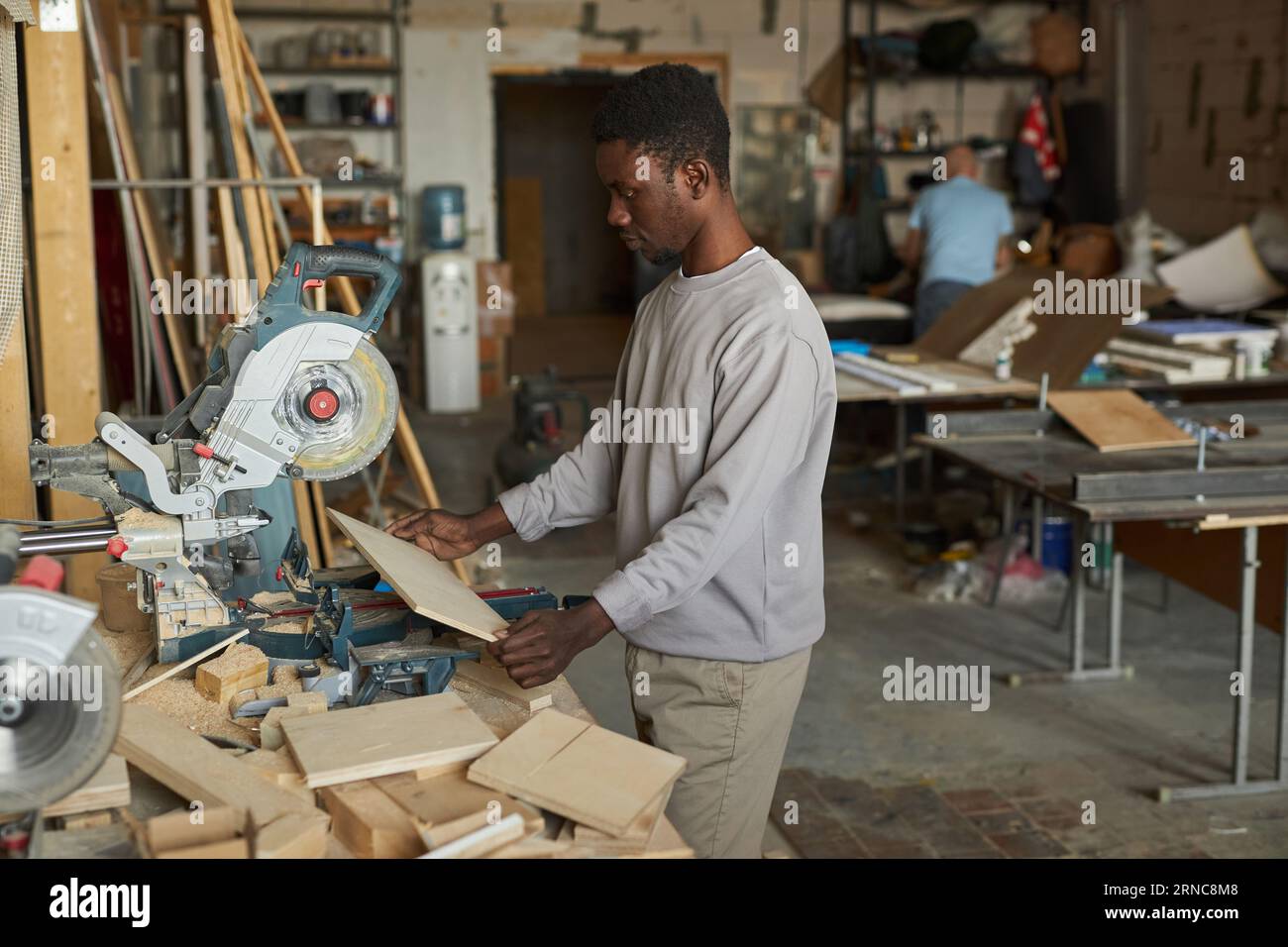 Side view portrait of black man cutting wood in home worshop, copy ...