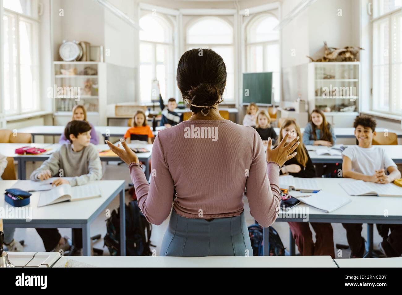 Rear view of female teacher explaining students sitting in classroom Stock Photo - Alamy