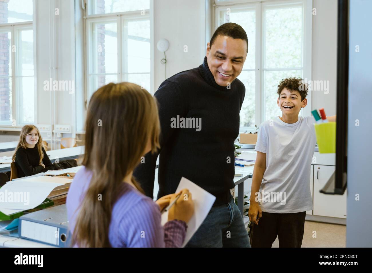 Happy male teacher having fun with students while teaching in classroom ...
