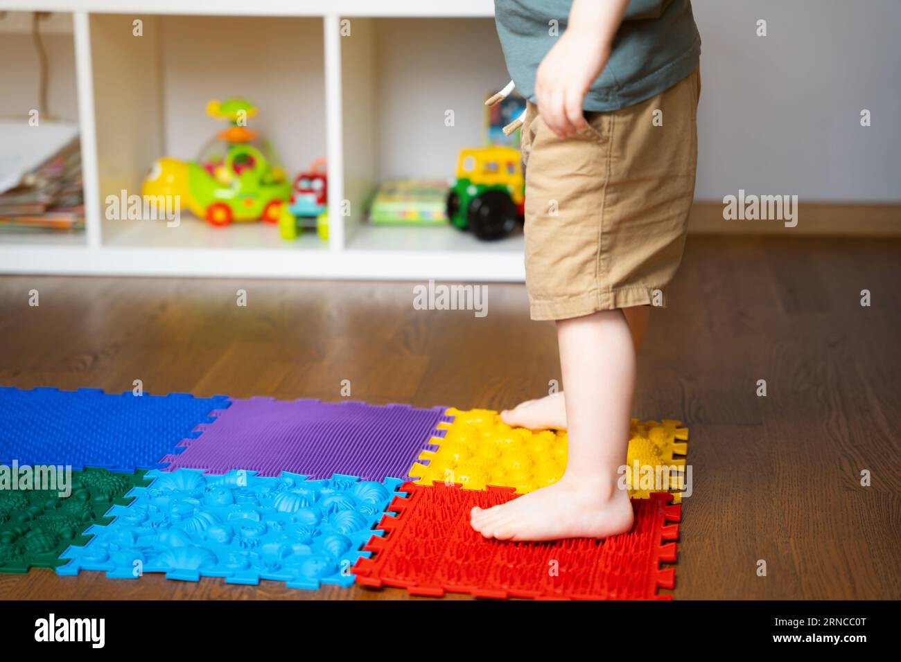 The toddler boy walks on an orthopedic mat that prevents flat feet ...