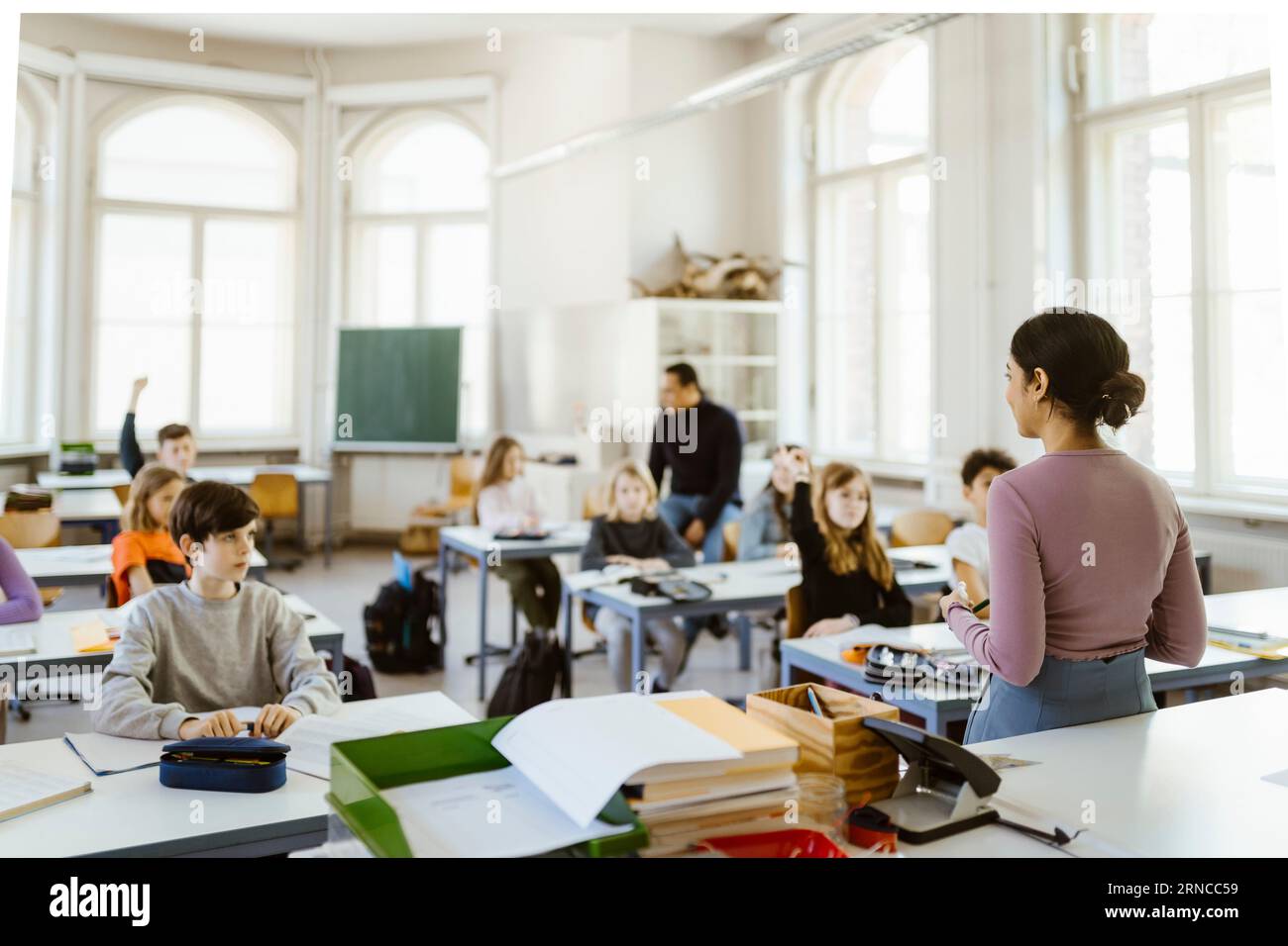 Female teacher teaching students sitting in classroom Stock Photo - Alamy