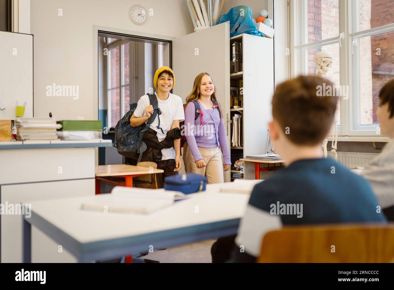 Smiling male and female students entering in classroom Stock Photo - Alamy