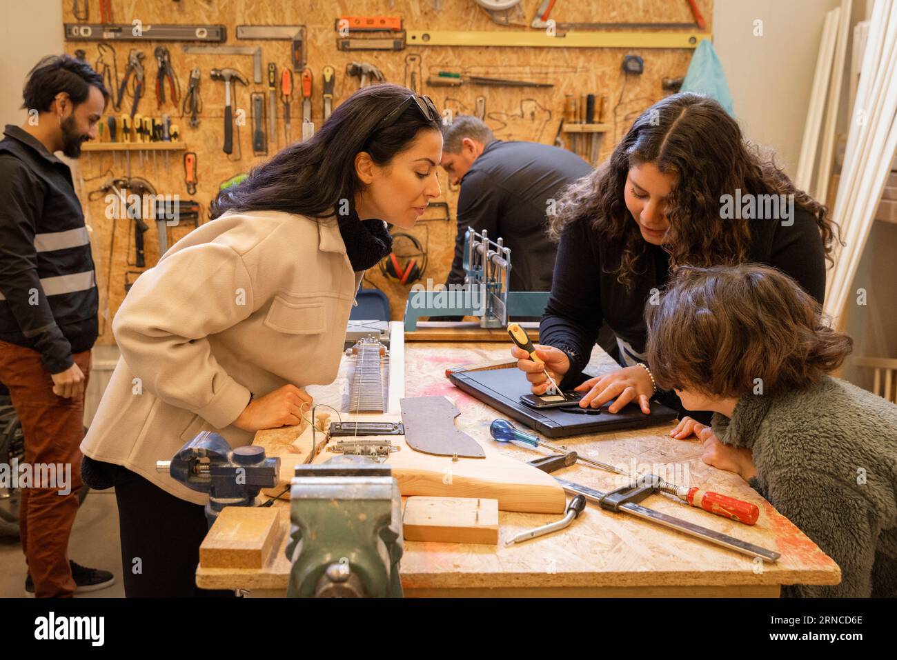 Female technician explaining smart phone repair to mother and son at ...