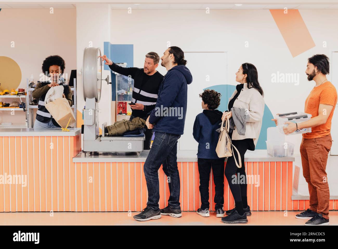 Male and female customer exchanging reused goods at recycling center ...