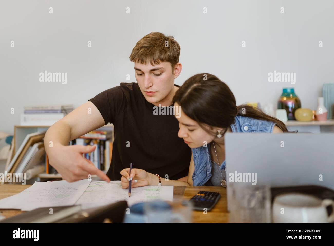 Man pointing at book while studying together Stock Photo - Alamy