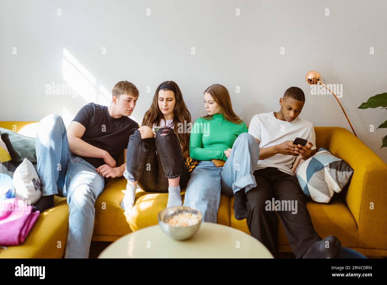 Young multiracial friends using smart phones while sitting together on ...