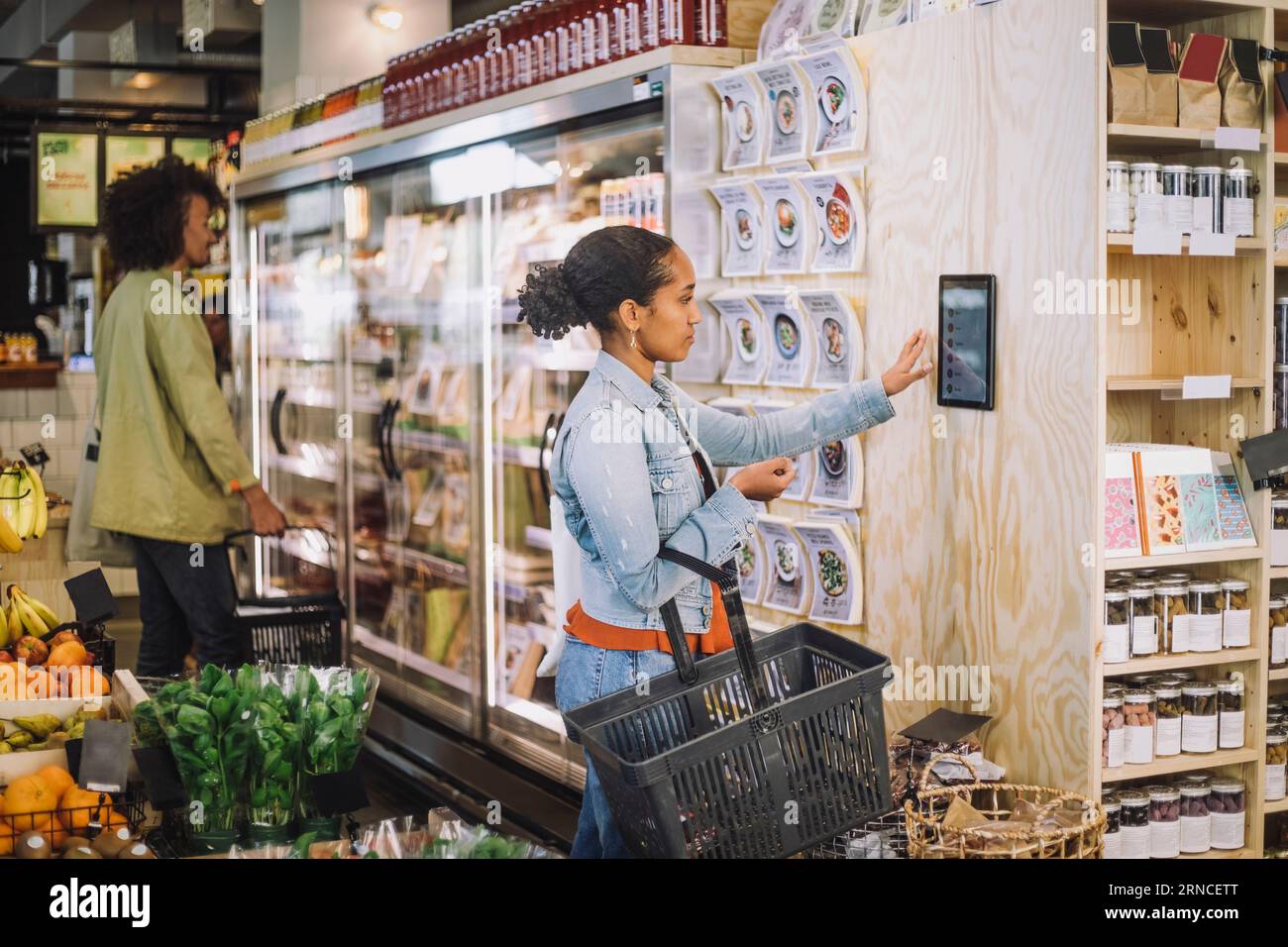 Side view of female customer using digital tablet mounted on wall at ...