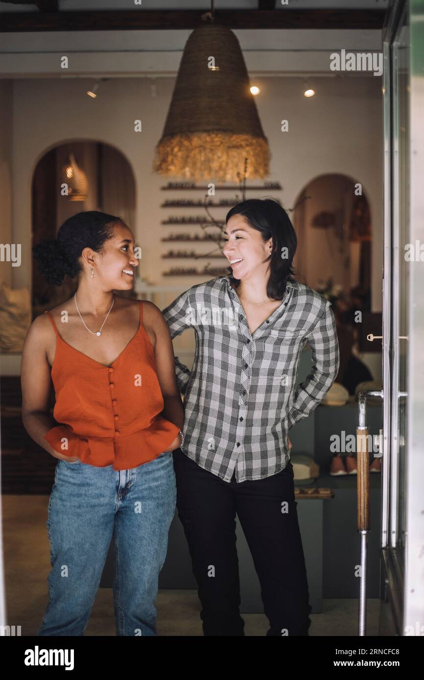 Happy multiracial female sales colleagues standing together at fashion ...