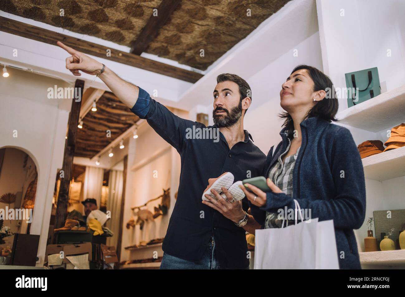 Salesman pointing to female customer in clothing store Stock Photo - Alamy