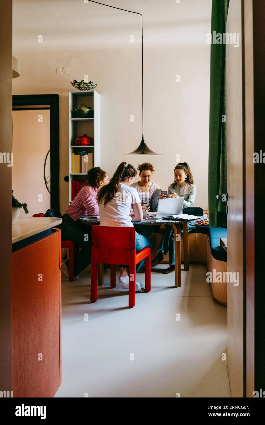 Female friends doing homework together while studying at home Stock ...
