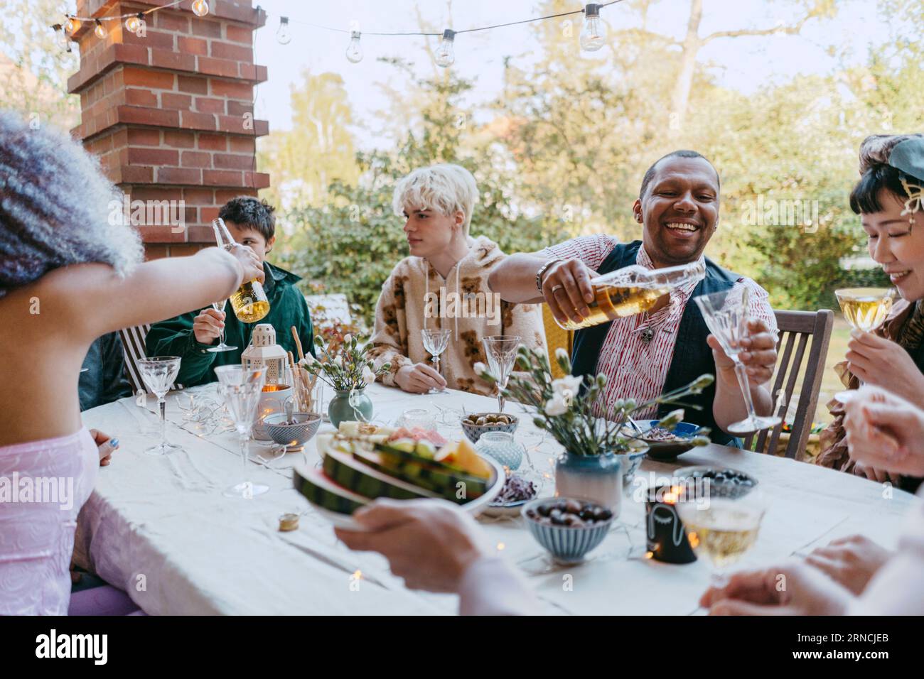 Happy friends of LGBTQ community drinking wine while sitting at table ...