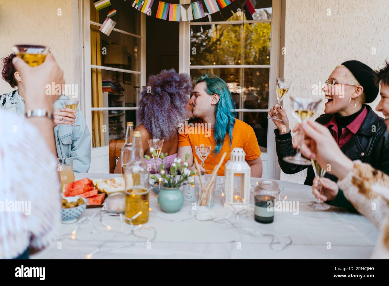 Romantic transwoman kissing gay friend during dinner party in back yard ...