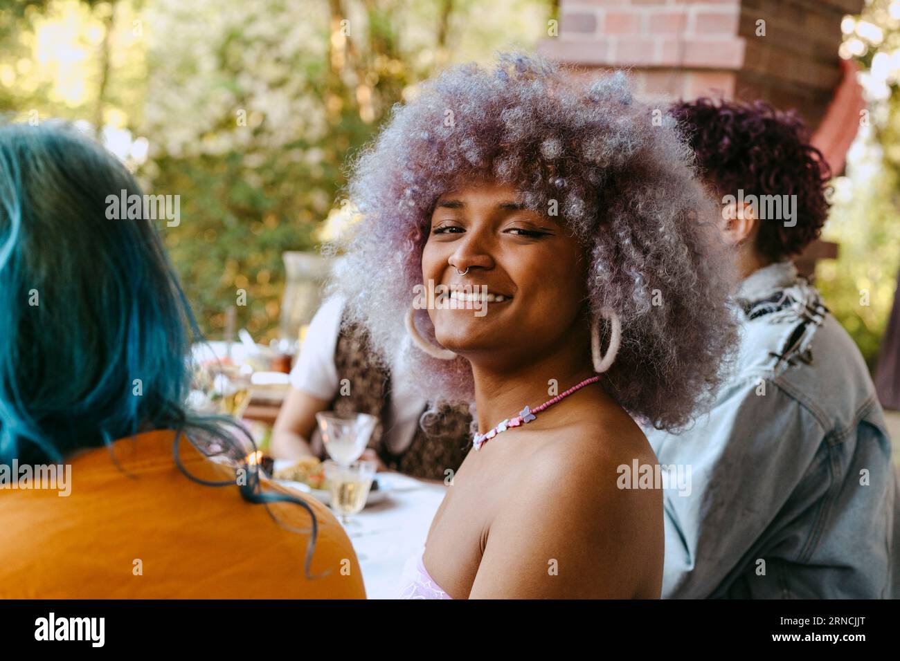 Side view portrait of smiling transwoman with curly hair during dinner ...