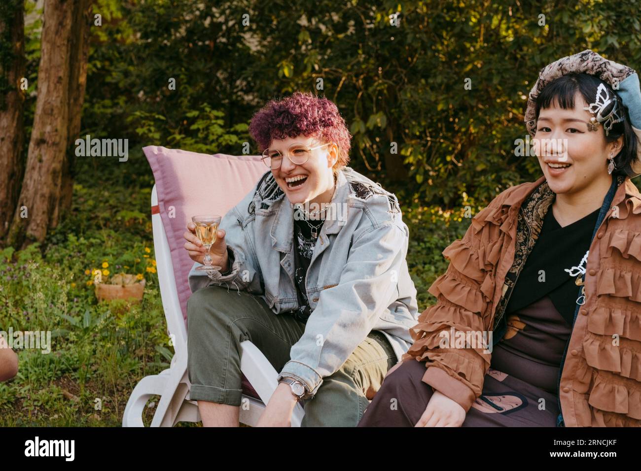 Happy non-binary person having drinks with friend during dinner party ...