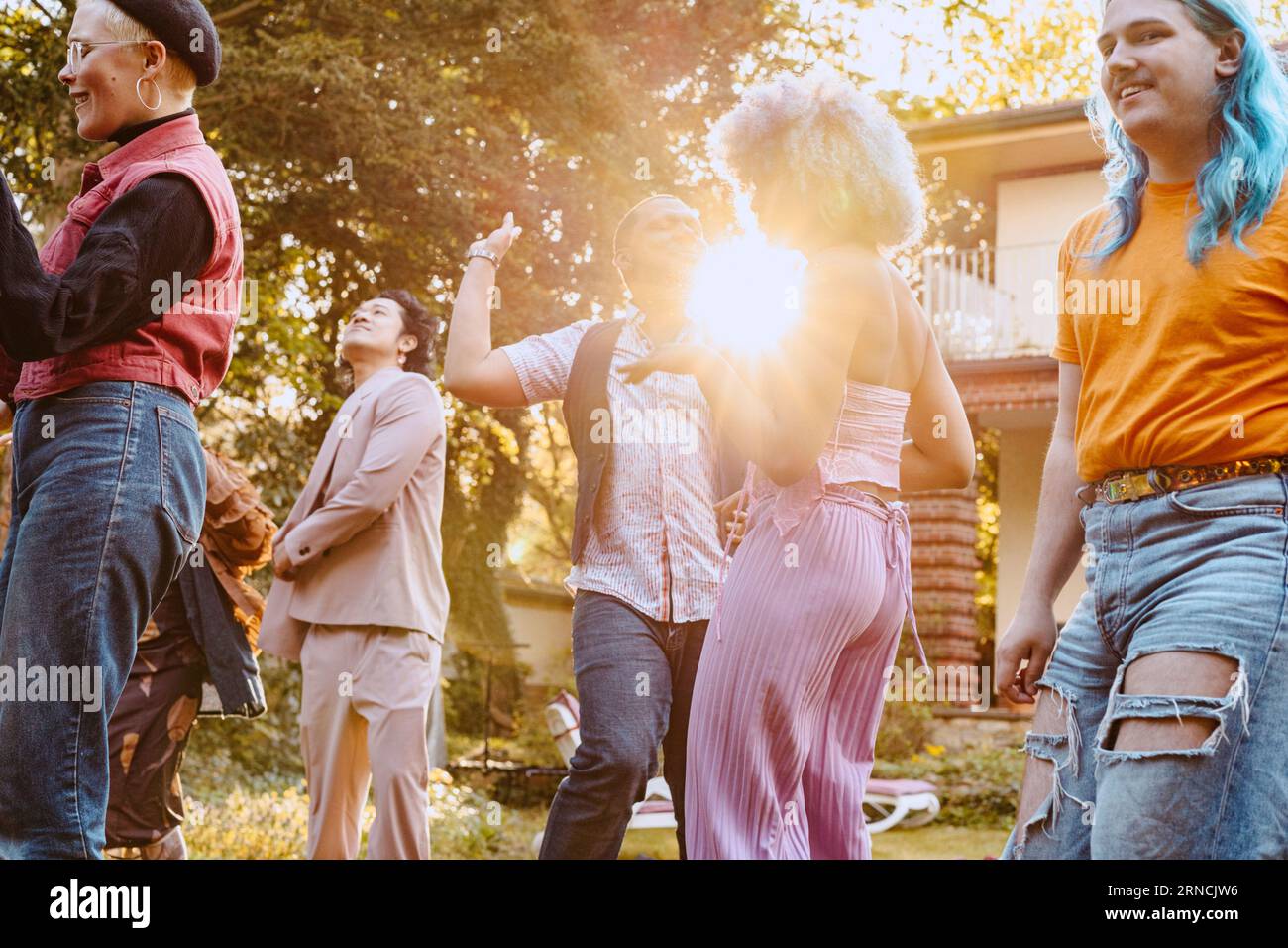 Happy friends of LGBTQ community dancing together during dinner party ...