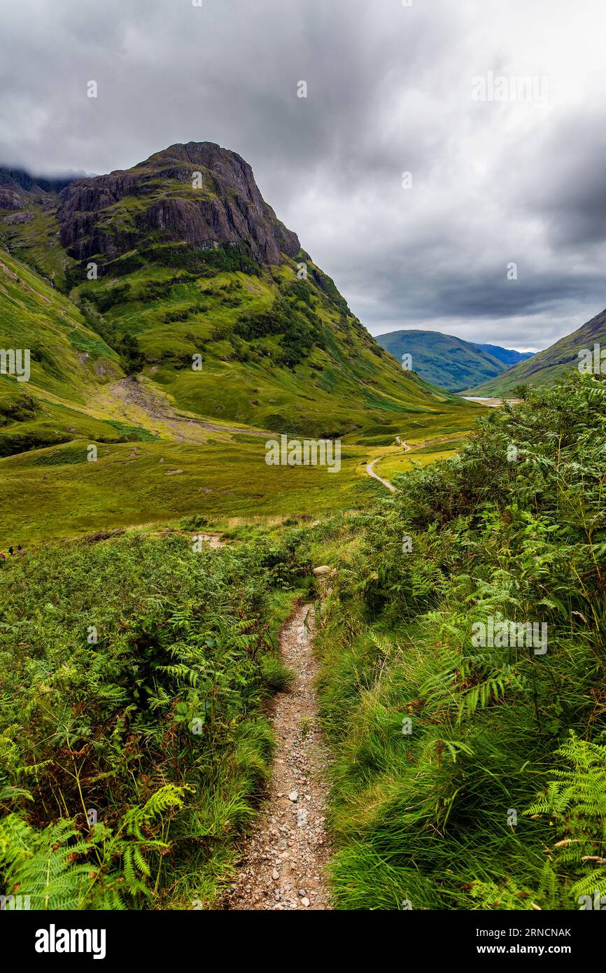 Hiking trail leading into a valley surrounded by steep mountains and a ...