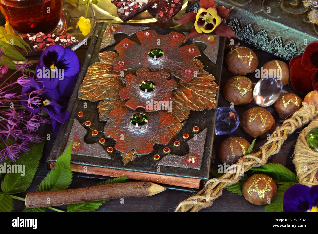 Still life with magic book of spells, runes and flowers on witch ritual ...