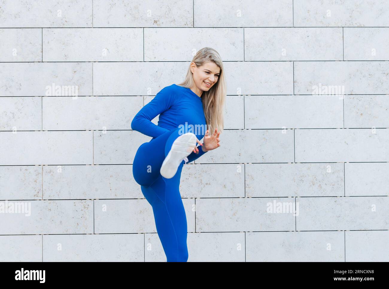 Fitness sport woman doing stretching exercise over gray wall. Horizontal sport theme poster ...