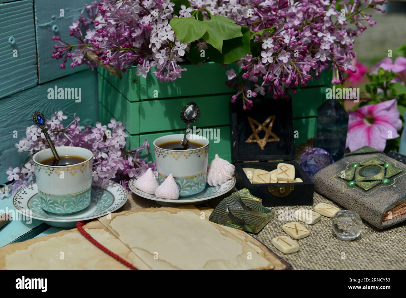 Vintage still life with open book or diary, runes, cup and lilac ...
