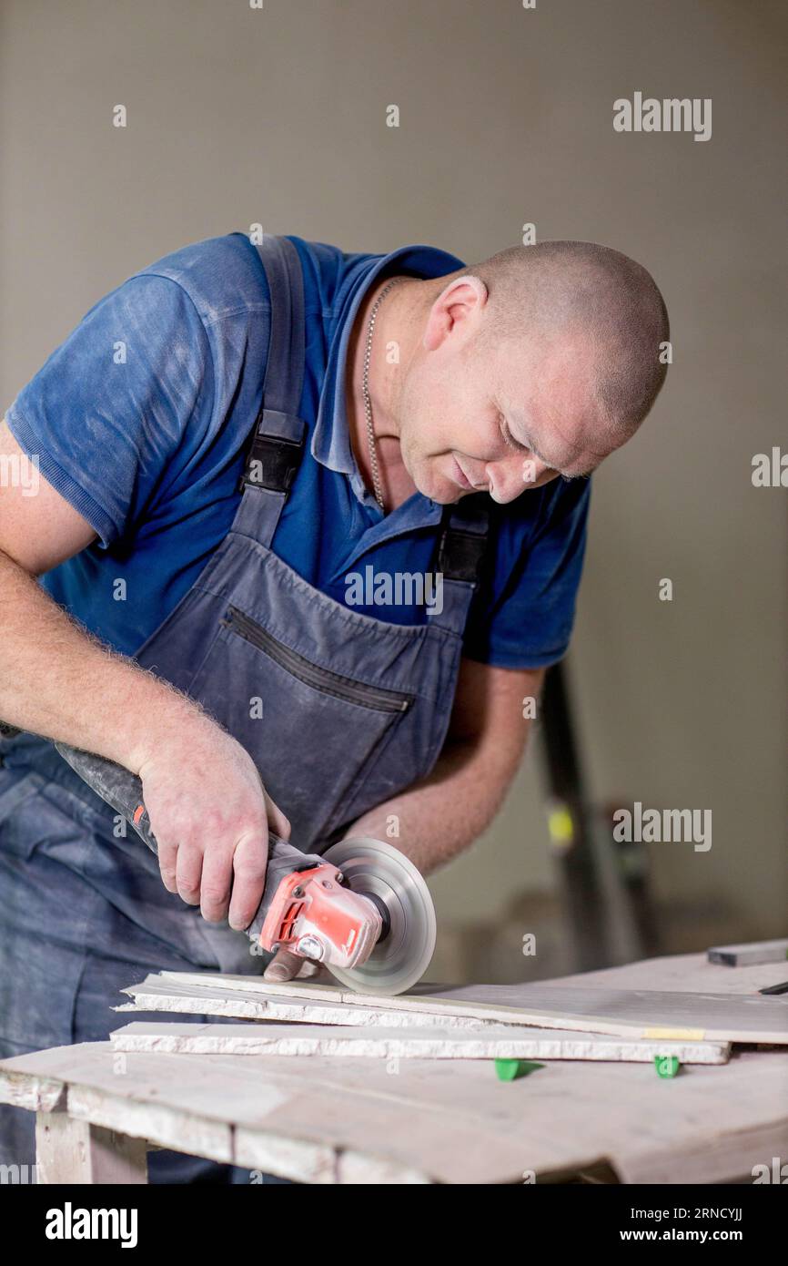 Professional tiler cutting tile with angle grinder. Construction ...