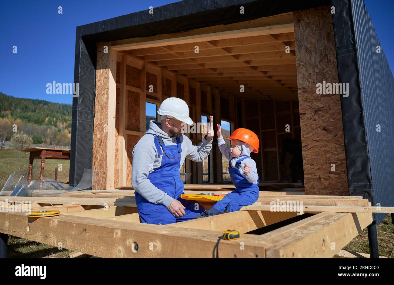Father with toddler son building wooden frame house. Male builder ...