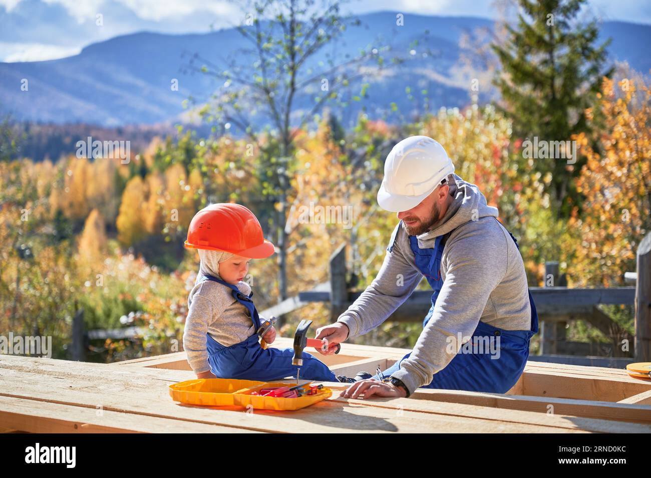 Father with toddler son building wooden frame house. Male builders ...