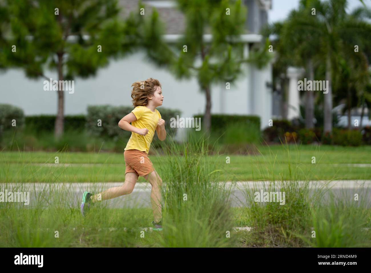 Cute kid boy running across american neighborhood street. Summer ...