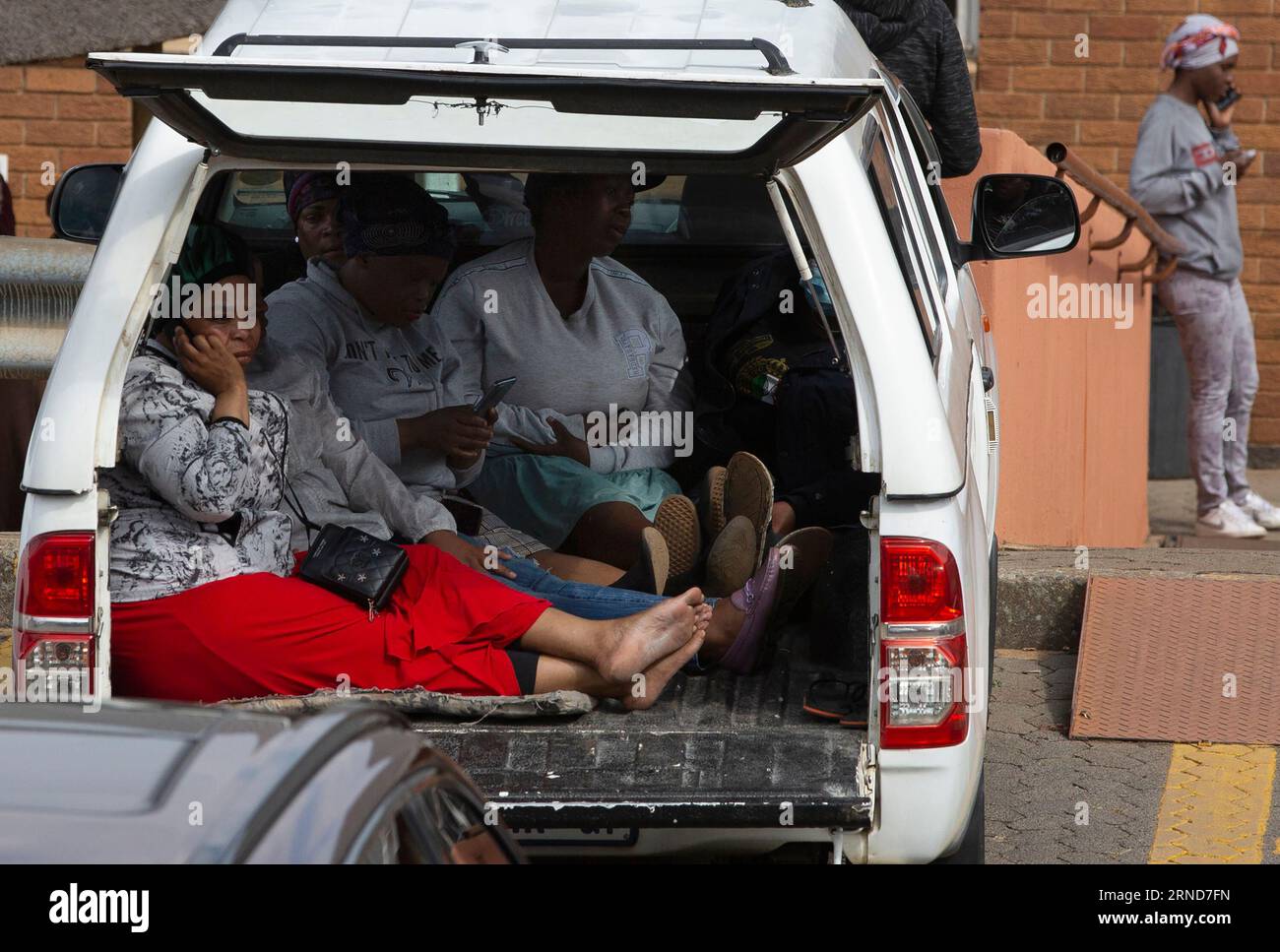 Women in the back of a truck wait at a forensic mortuary to identify ...