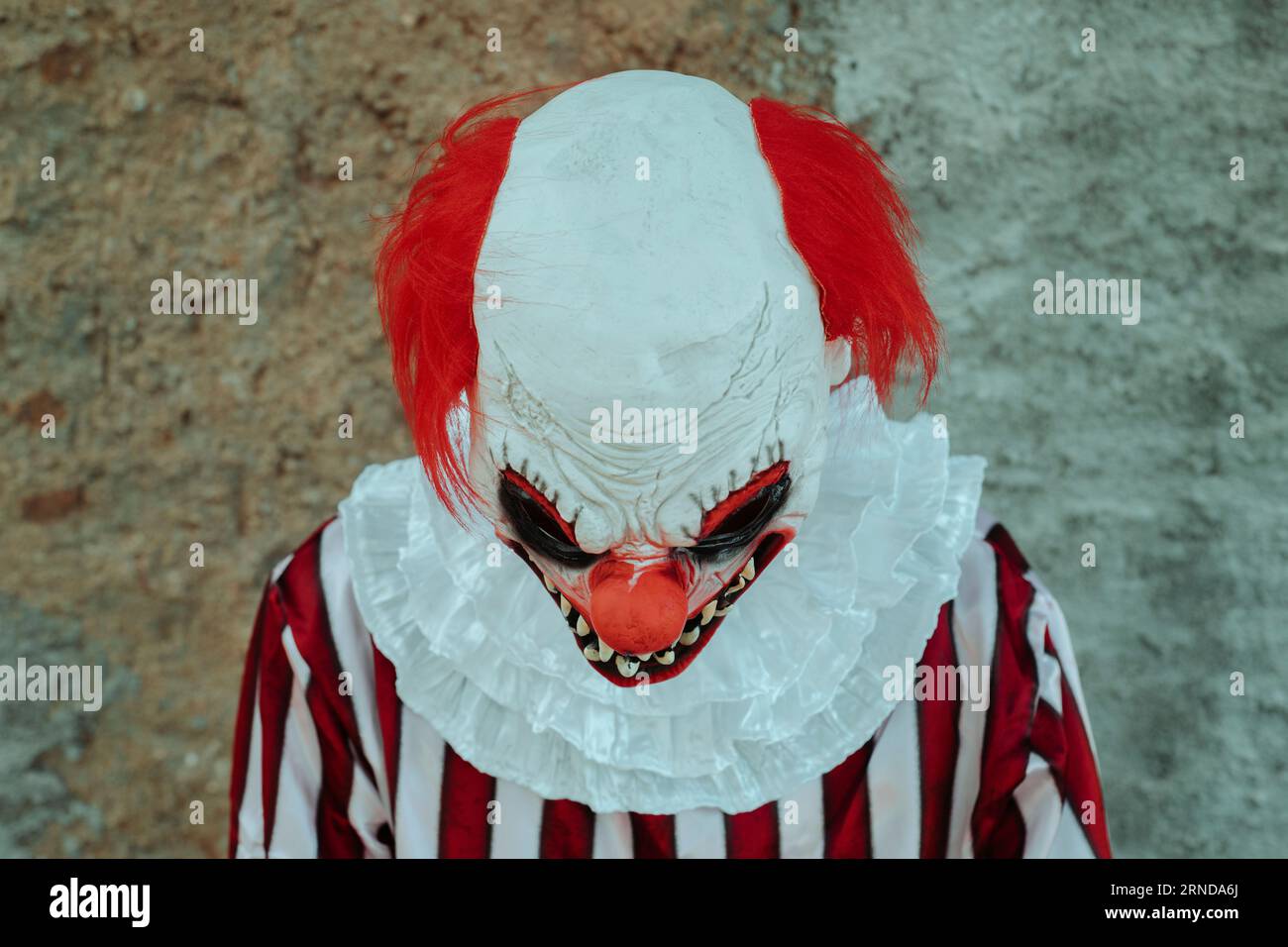 a mad evil redhead clown, wearing a white and red striped costume with ...