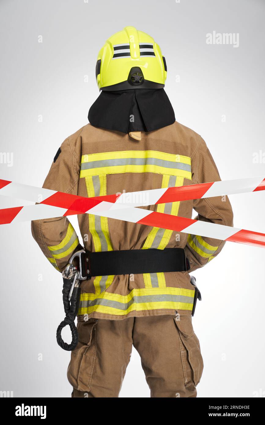 Strong unrecognizable firefighter in helmet standing behind red and ...